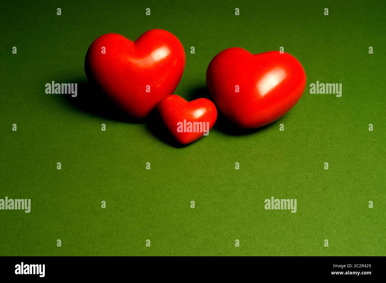 Two bigger and on smaller heart on a green background. With space for ...