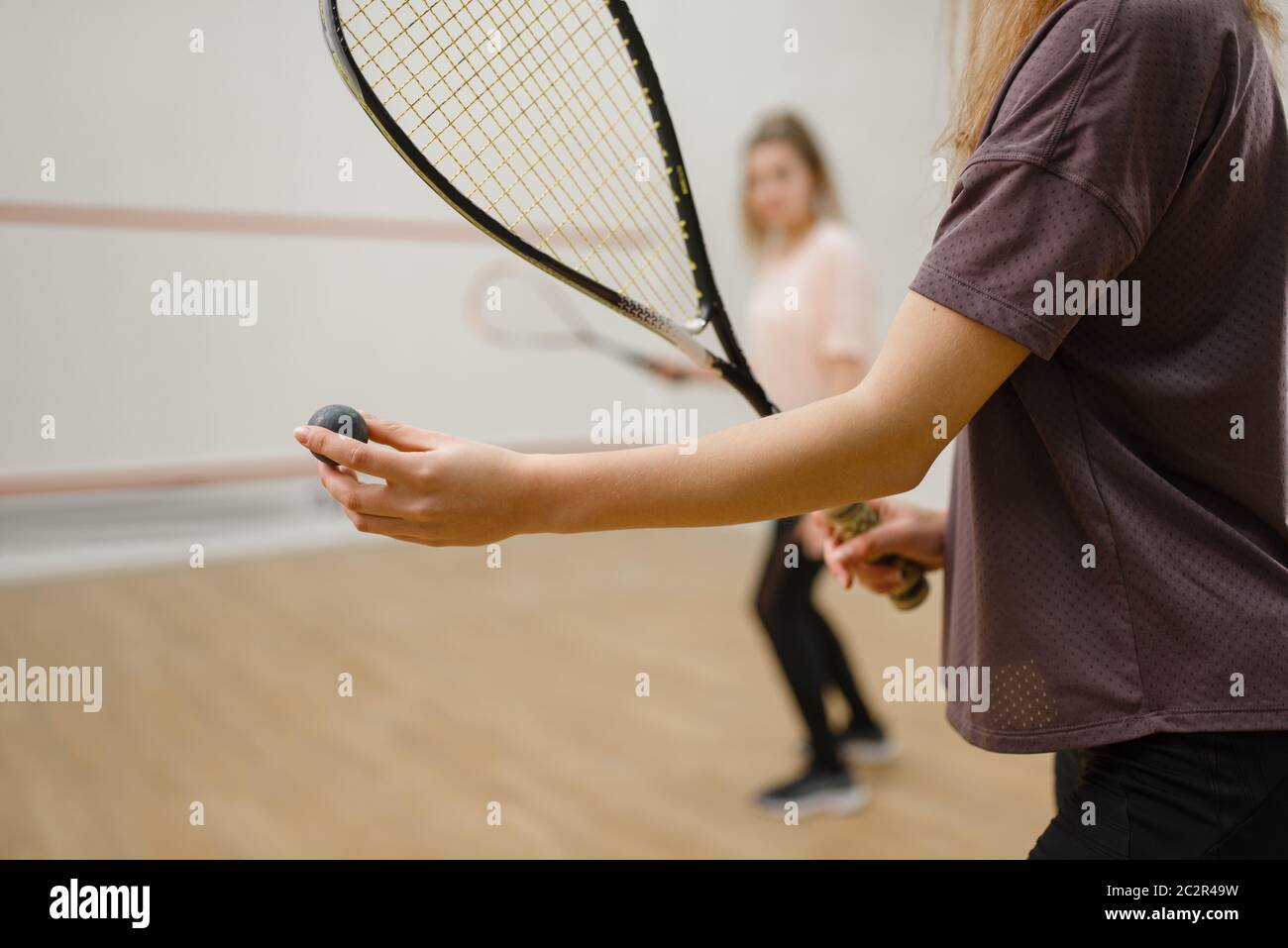 Two female players with squash rackets, focus on ball. Girls on ...