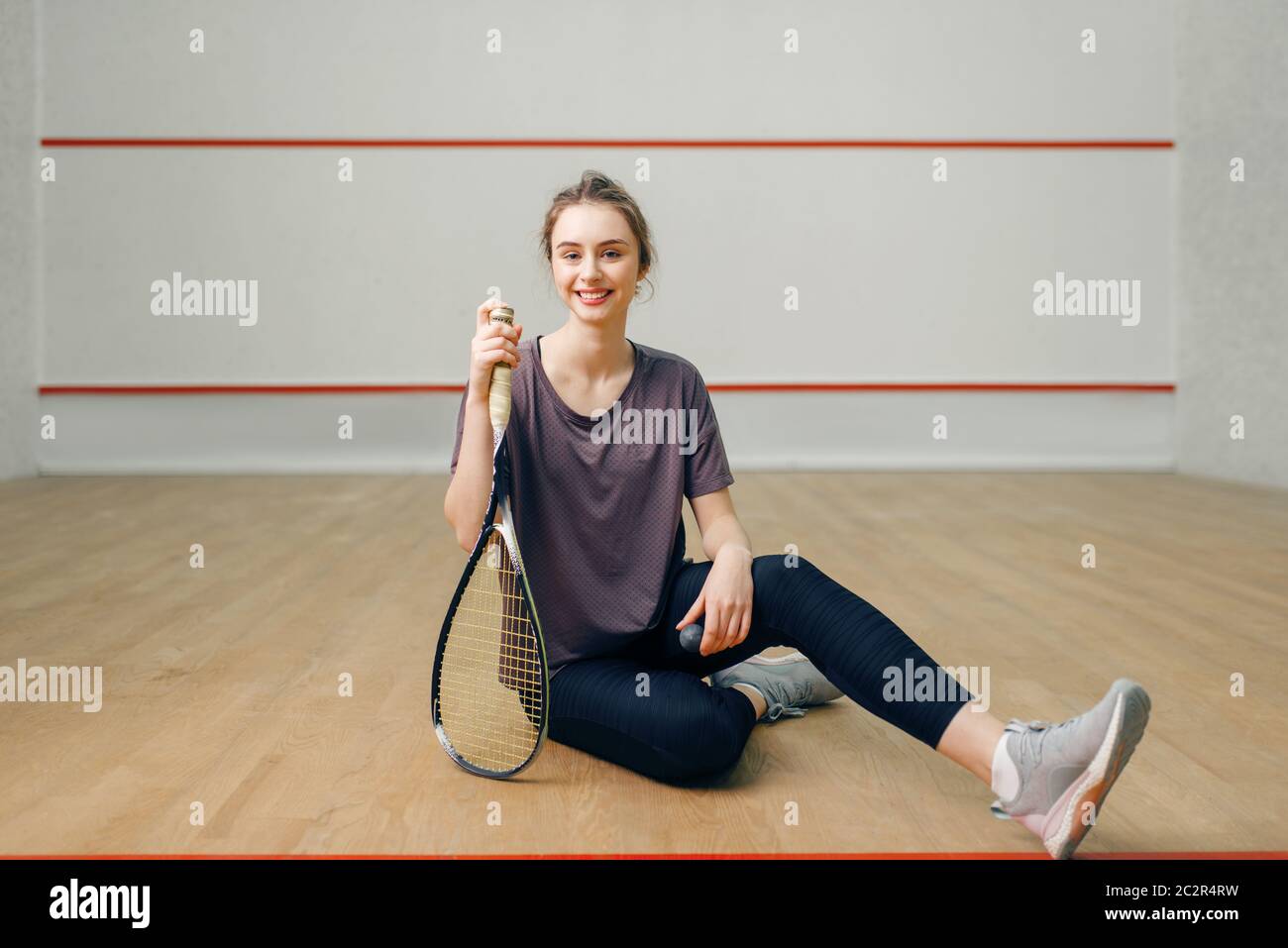 Female player with squash racket sitting on the floor. Girl on game ...