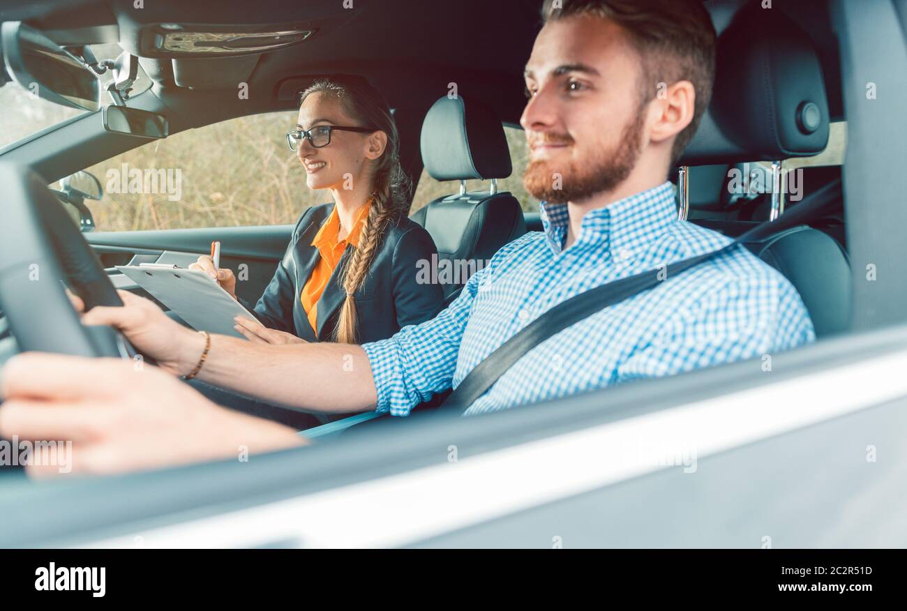 Driving instructor with student in school car teaching how to drive ...