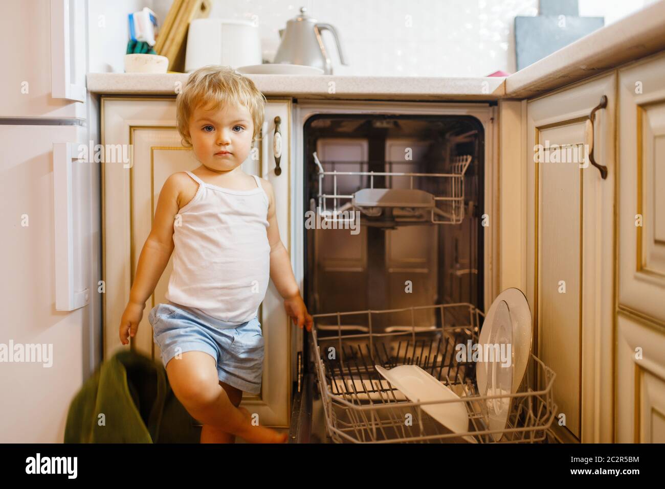 A little girl washing dishes on the kitchen. Baby doing housework at ...