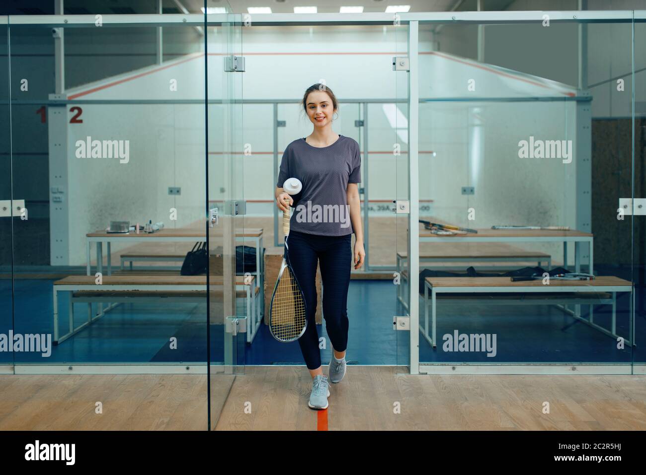 Happy female player with squash racket in locker room. Girl on game ...