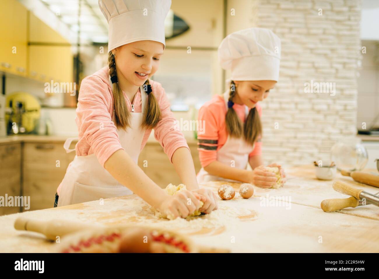 Two little girls chefs crumple the dough, cookies preparation on the ...