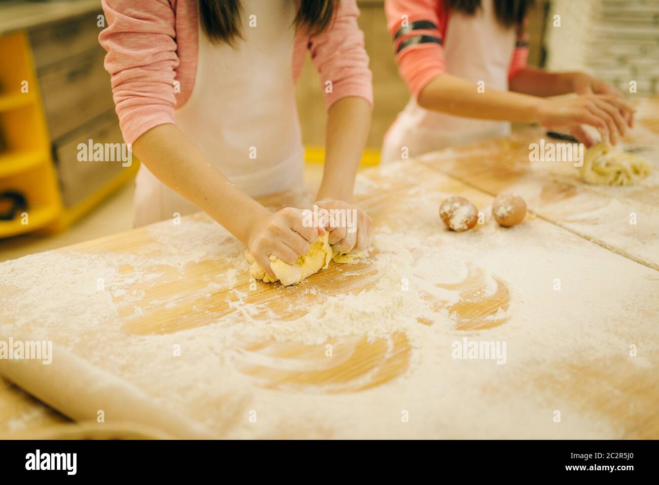 Two little girls chefs crumple the dough, cookies preparation on the ...