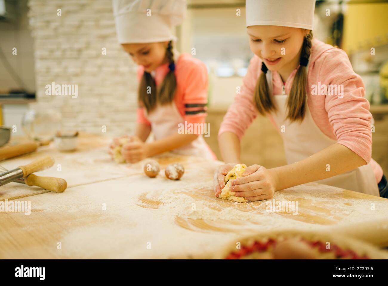 Two little girls chefs crumple the dough, cookies preparation on the ...