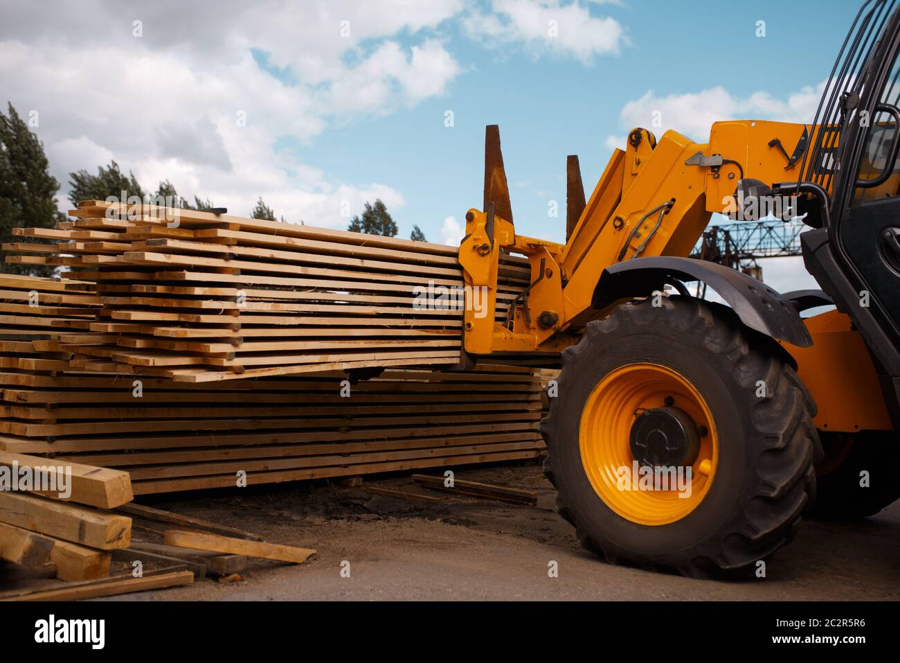 Forklift loads the boards in the lumber yard outdoor. Autoloader works ...