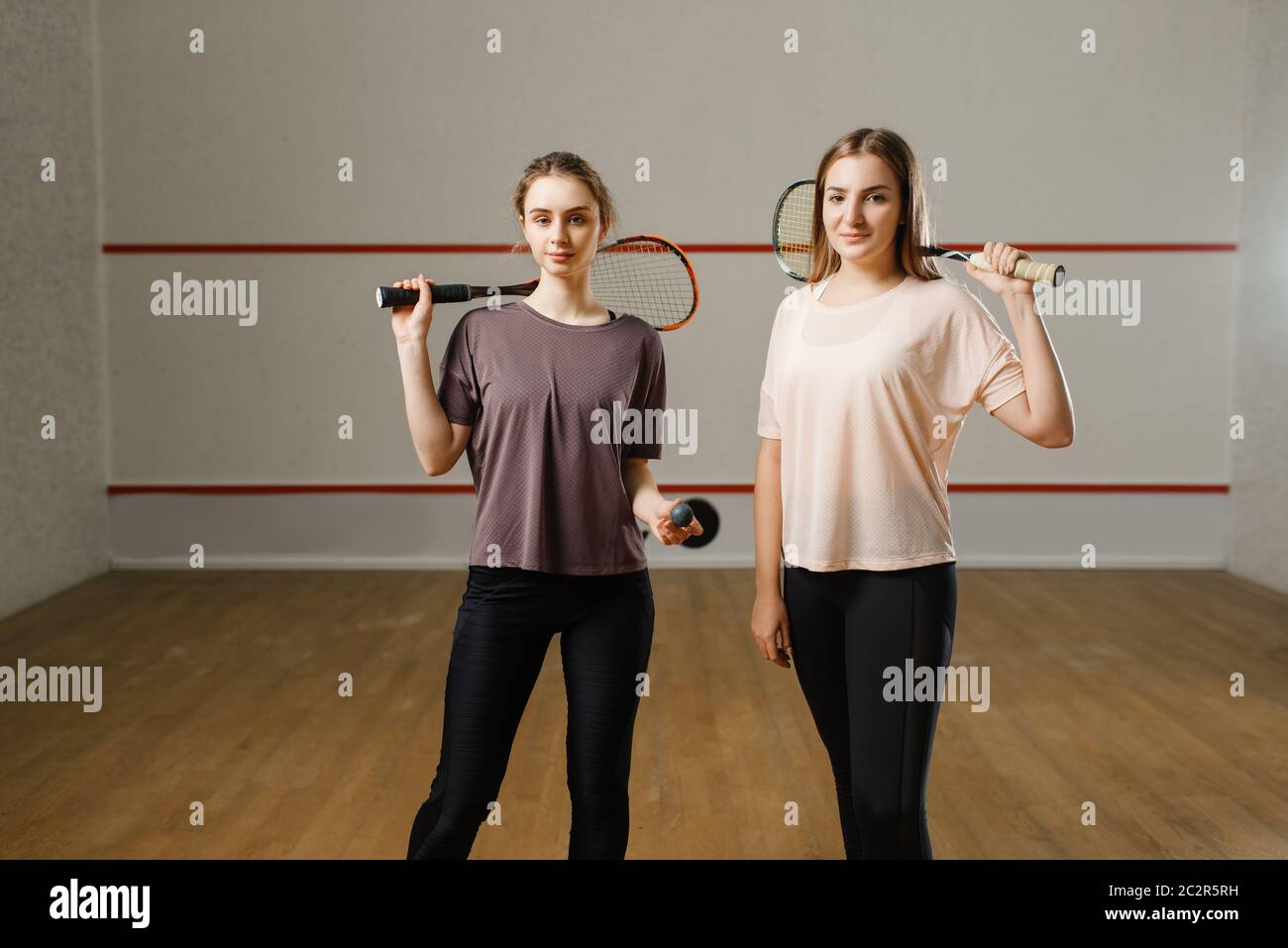 Two female players shows squash rackets. Girls on training, active ...