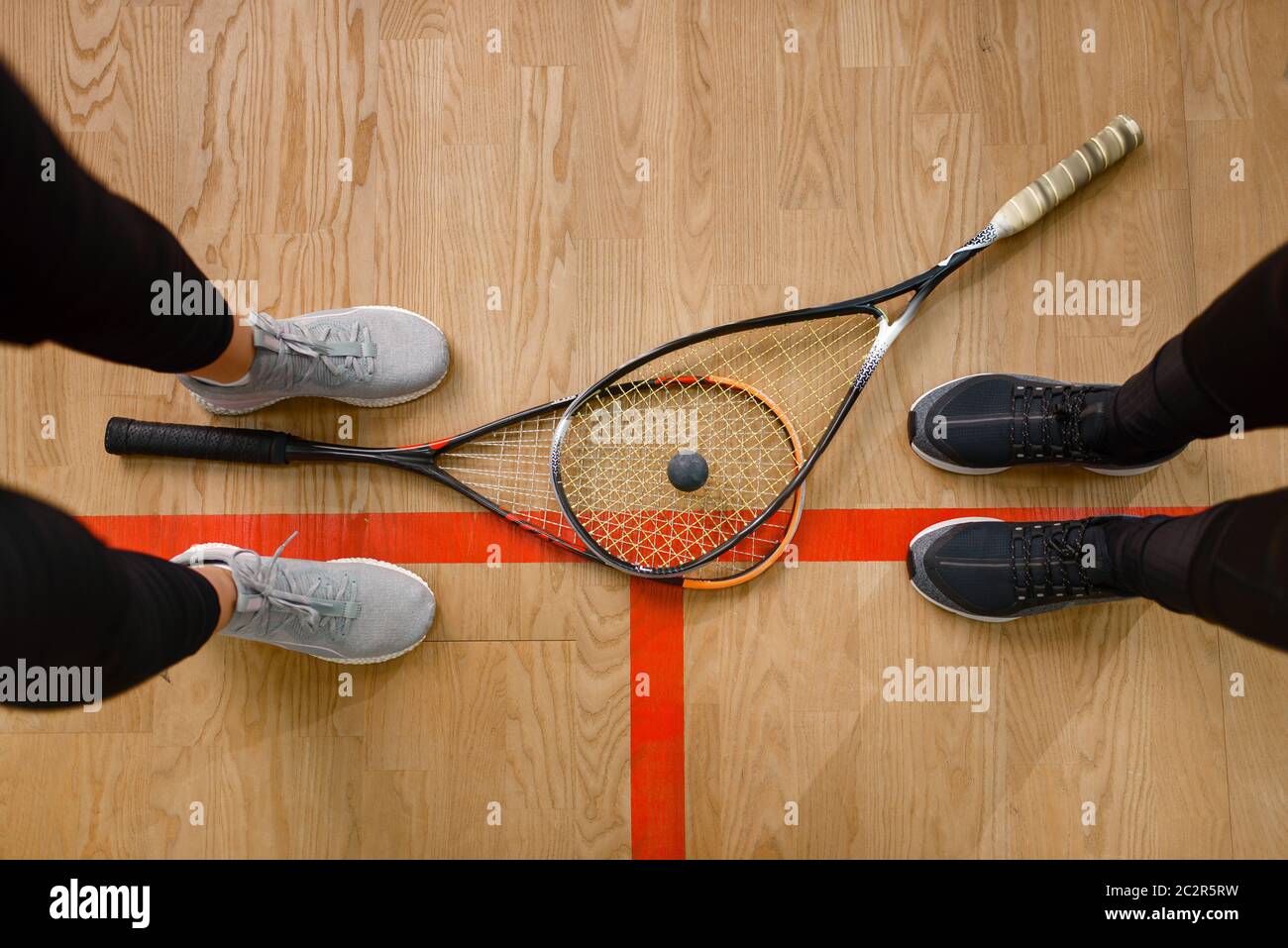 Two female players legs and squash rackets, top view. Girls on training ...