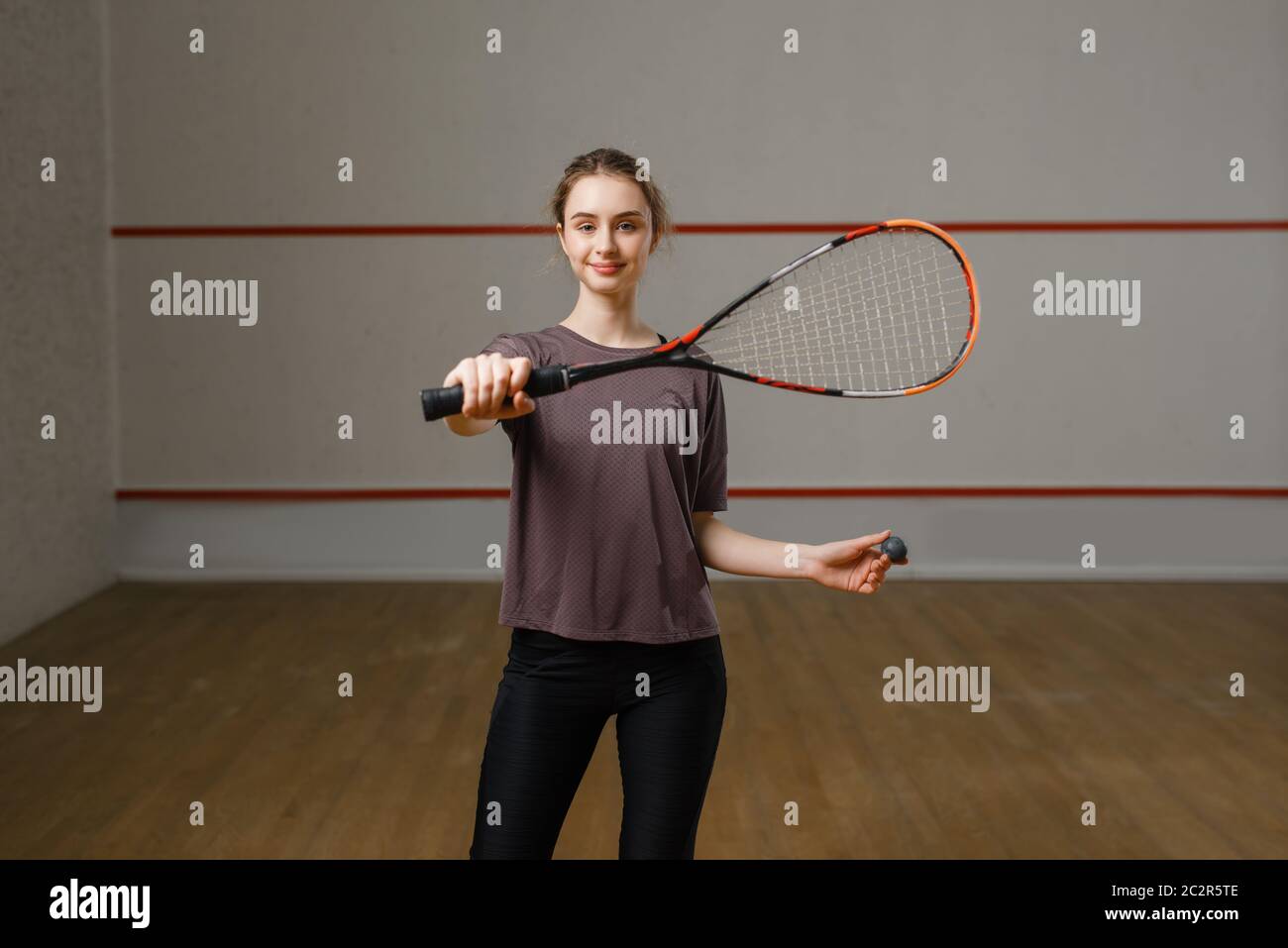 Female player shows squash racket on court. Girl on game training ...