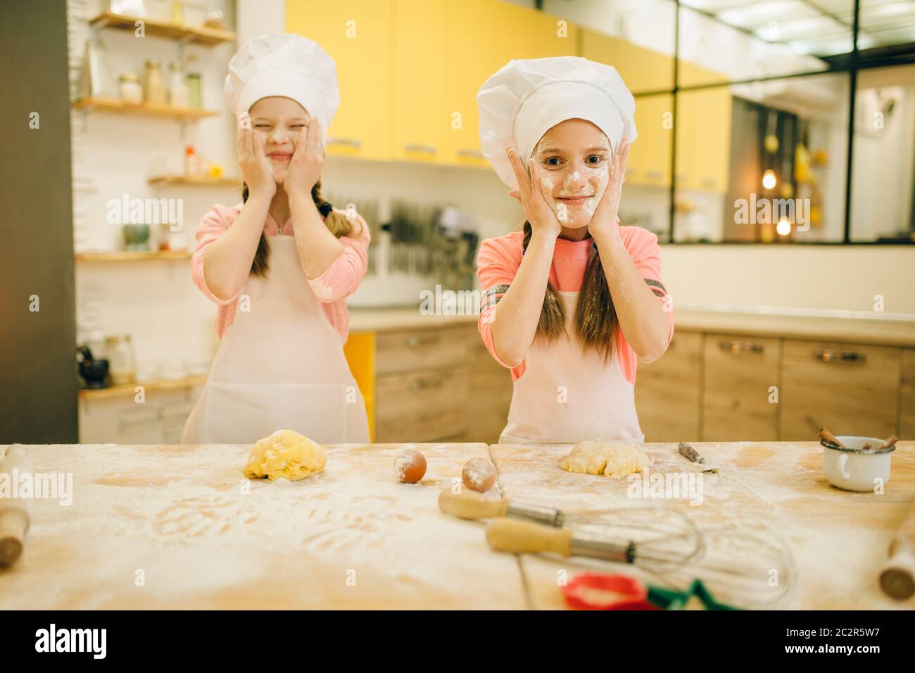 Two little girls chefs smears their faces with flour, cookies ...