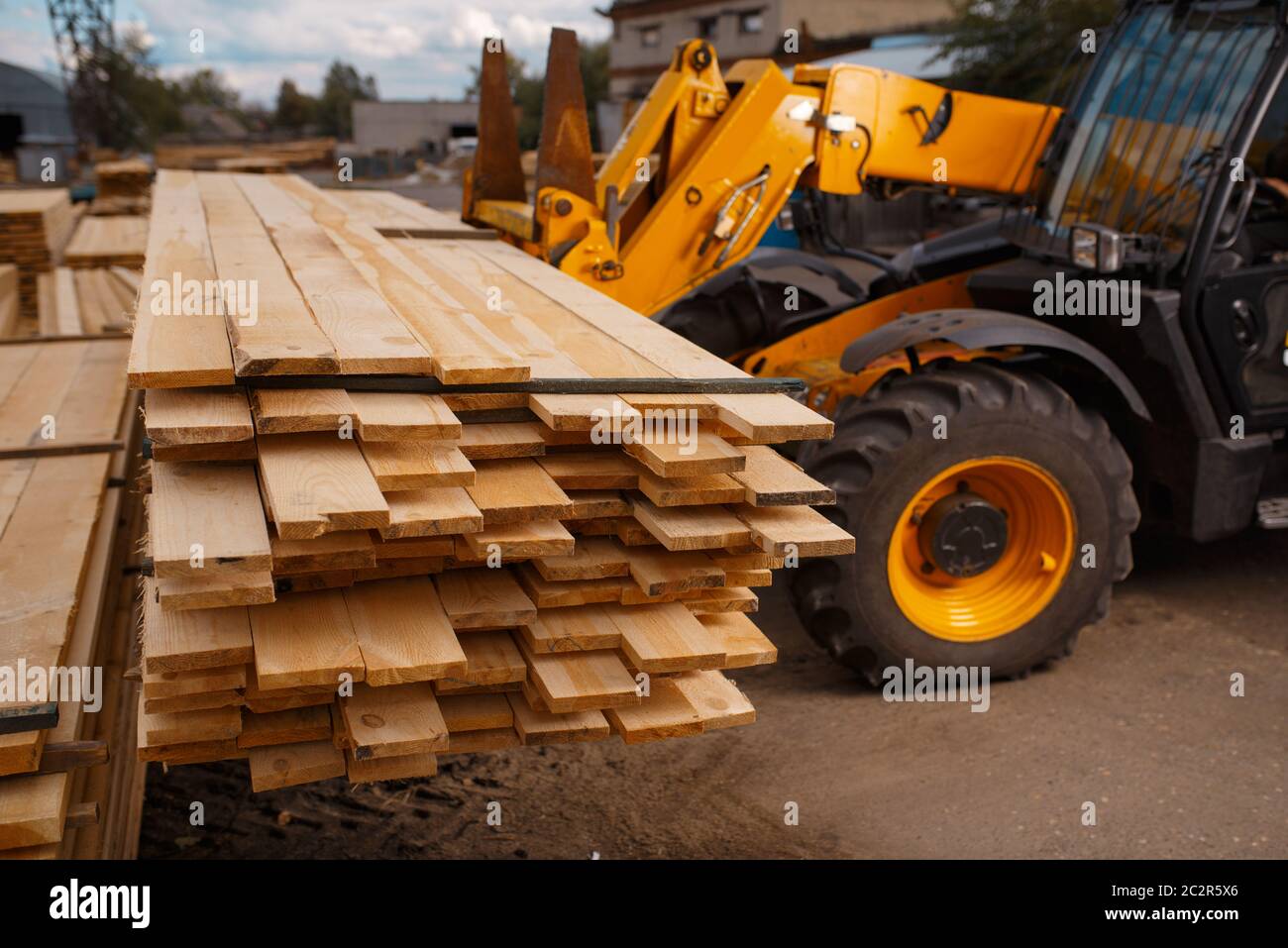 Forklift loads the boards in the lumber yard outdoor. Autoloader works ...