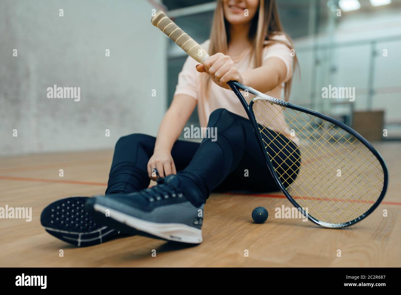 Female player legs, squash racket and ball. Girl on game training ...