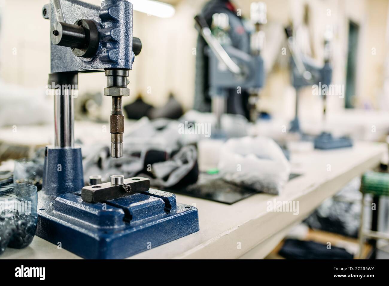 Clothing workshop, riverting machine on fabric, closeup. Dressmaking ...