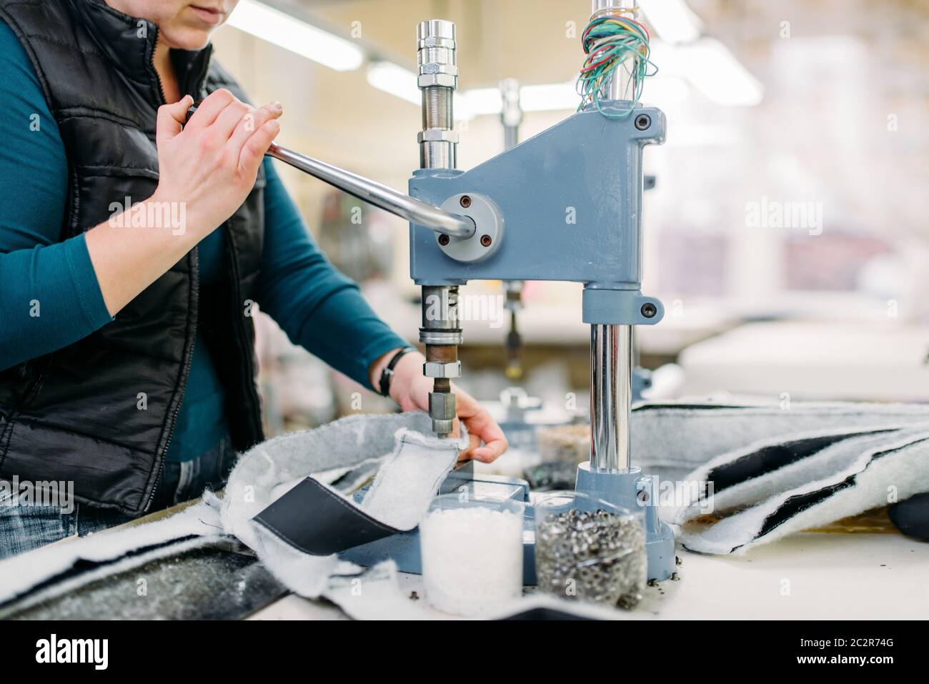 Female tailor works on riverting machine in workshop, clothing fabric ...