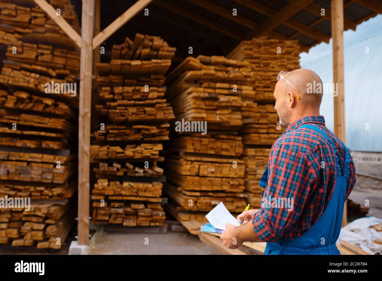 Joiner in uniform check boards on timber mill, lumber industry ...