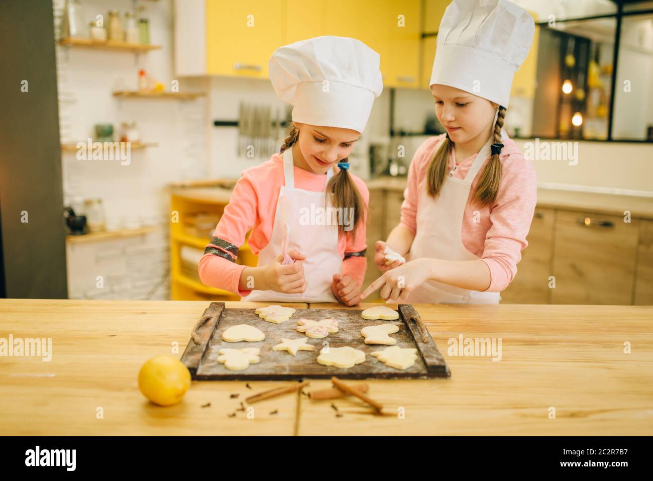 Two little girls cooks spread out cookies on a wooden board, bakery ...