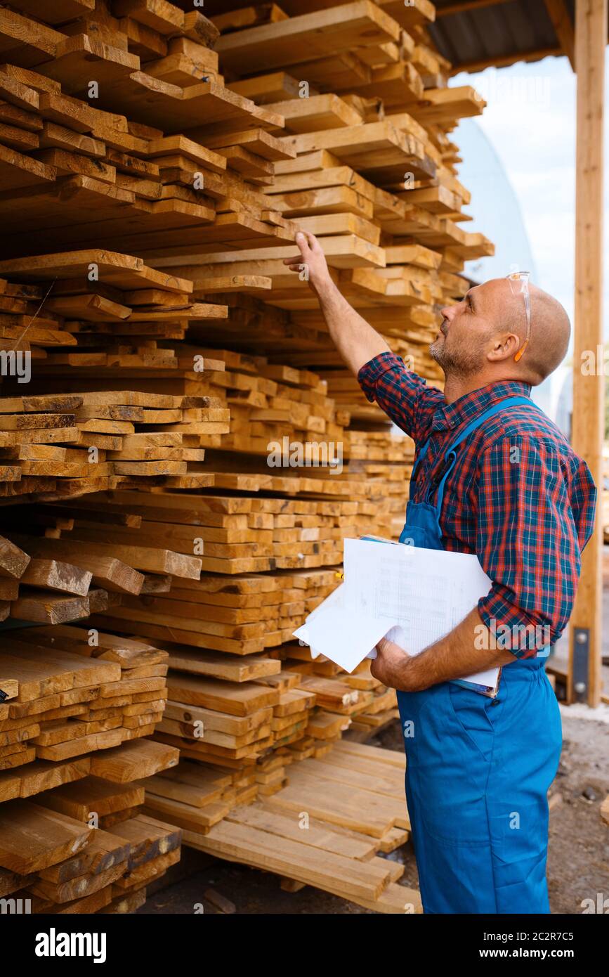 Carpenter in uniform check boards on sawmill, lumber industry ...