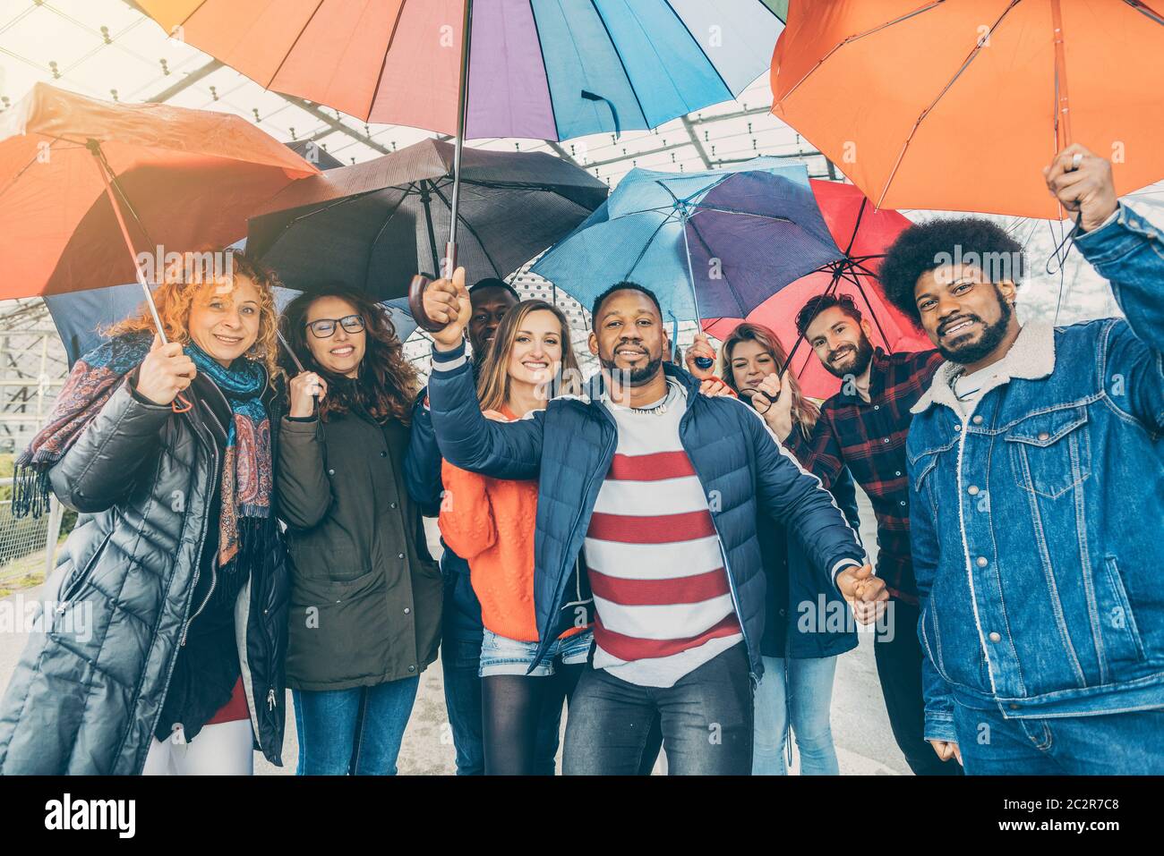 Friends making the best of rain and bad weather standing under ...
