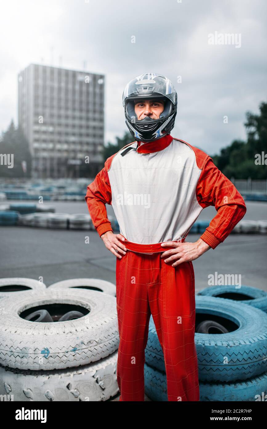 Kart driver with helmet in hands, karting track on background. Go-kart ...