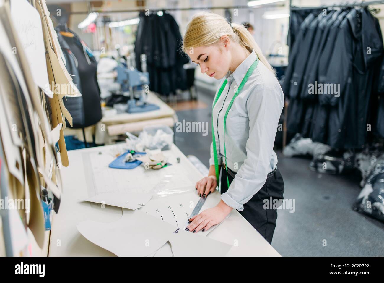 Clothes designer measures a pattern, manufacture on sewing factory ...