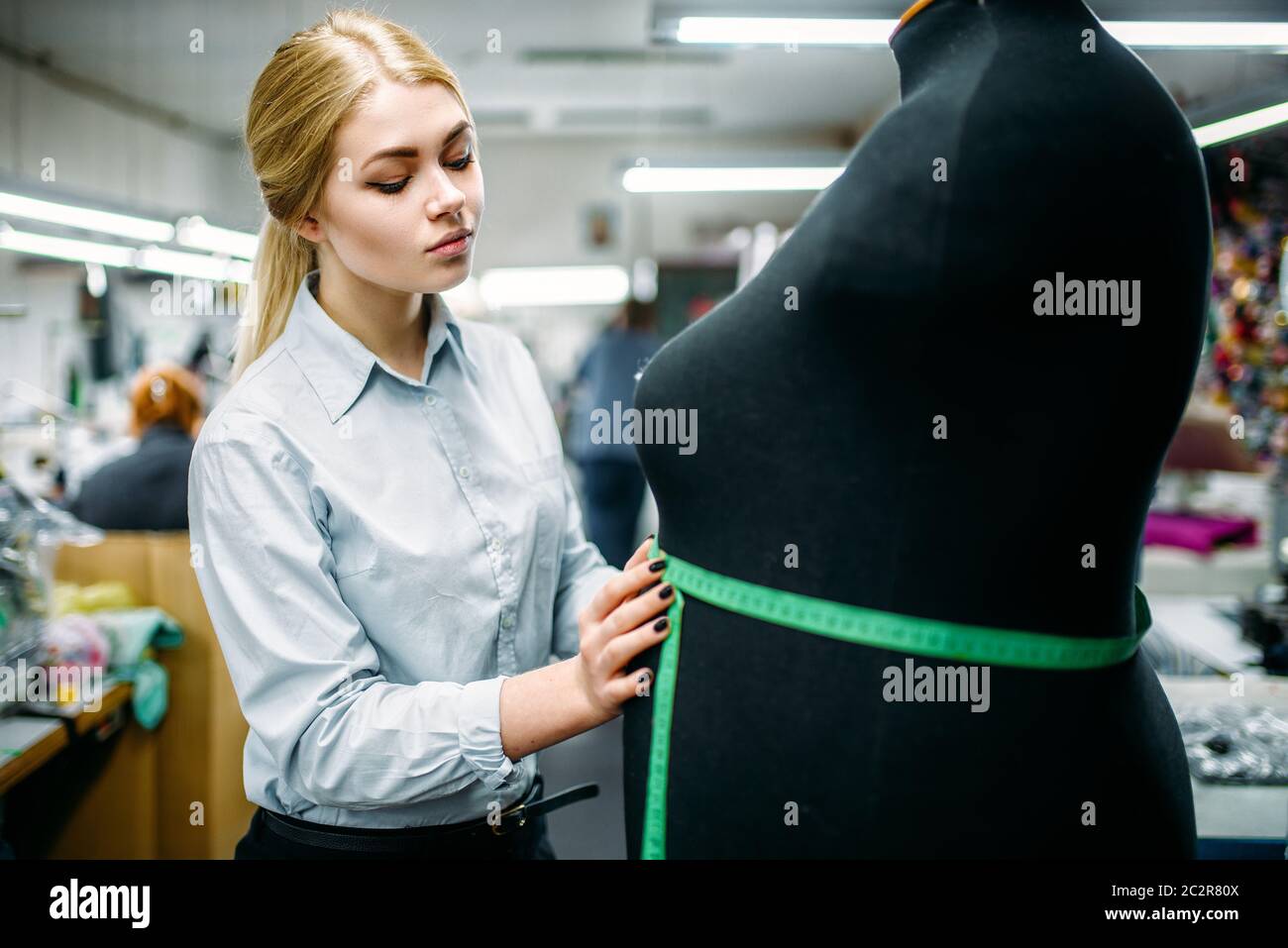 Clothes designer measures a dress on mannequin, manufacture on sewing ...