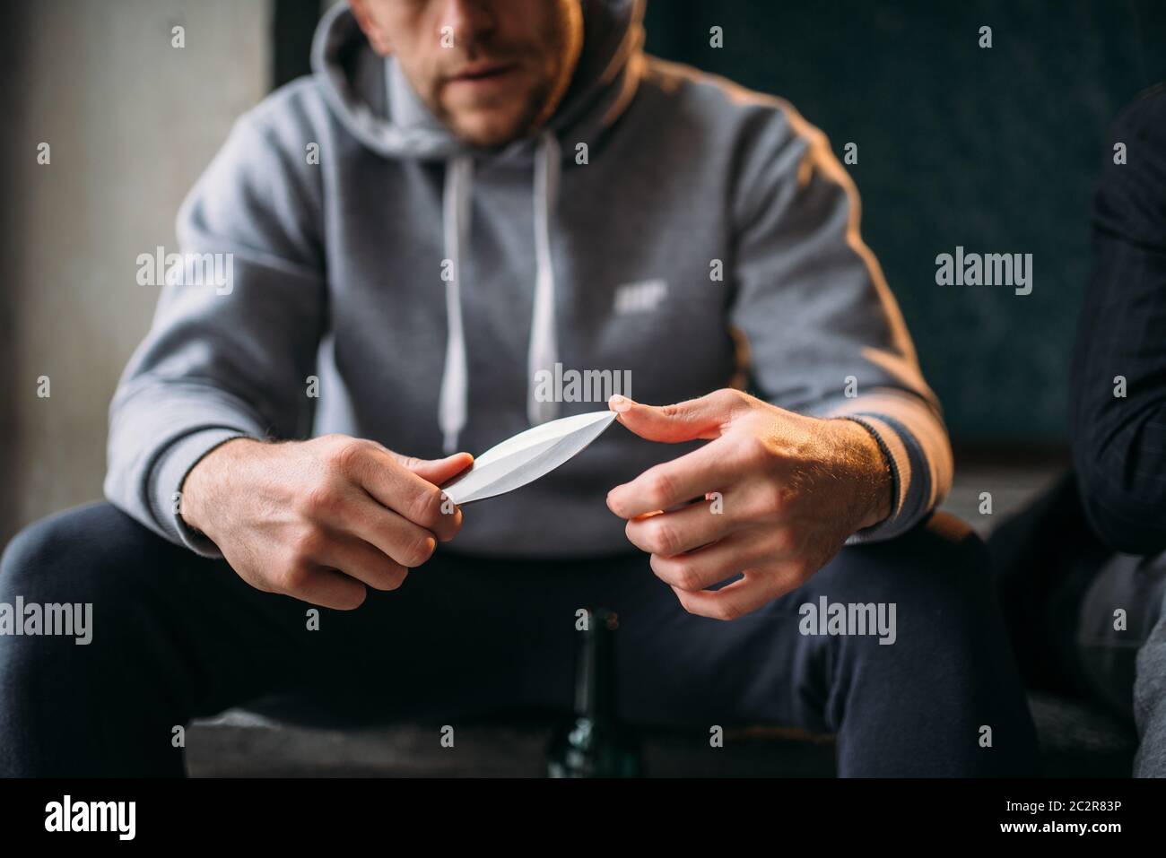 Male robber with knife sitting on the stairs. Street bandits with ...