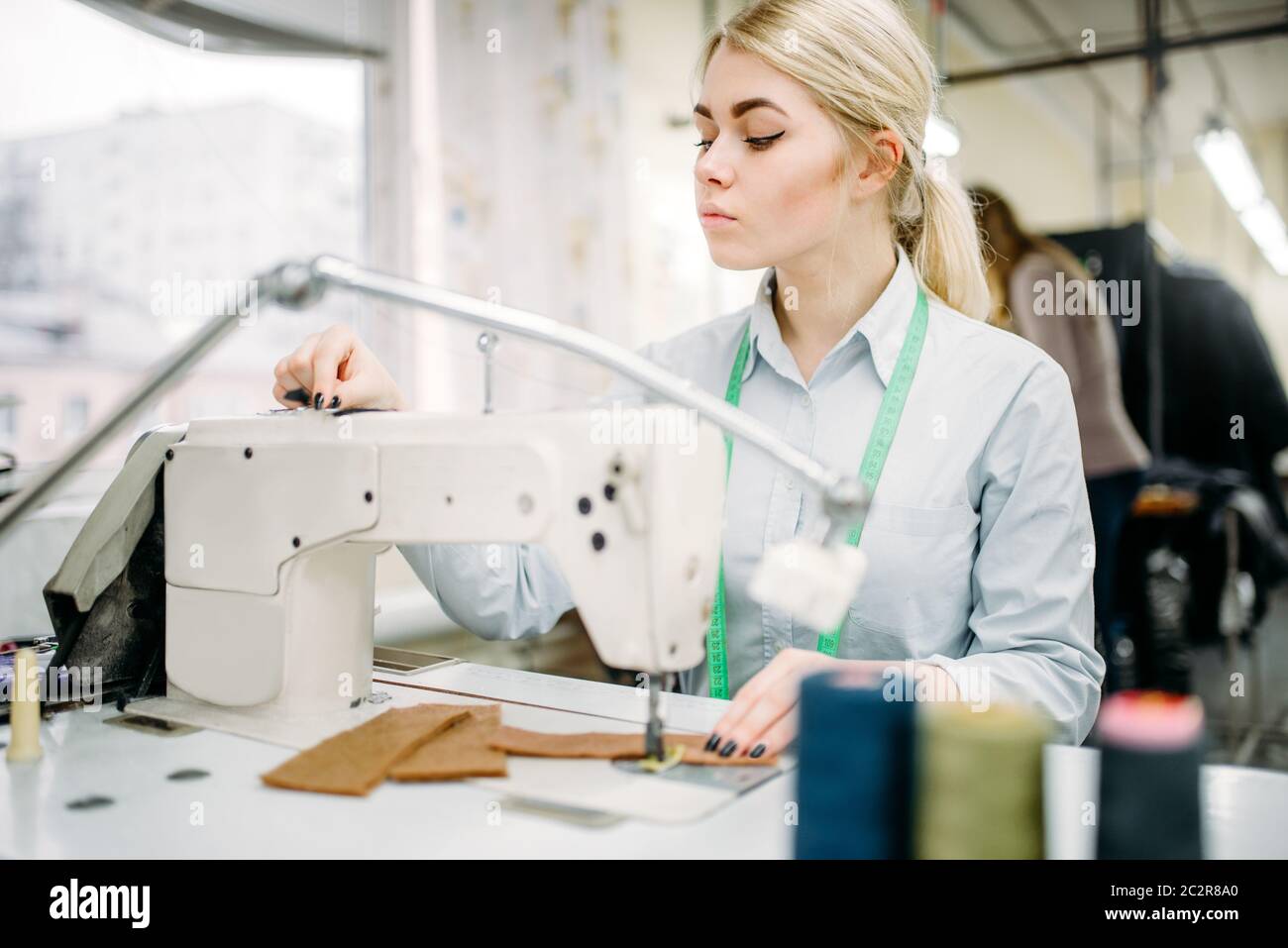 Female dressmaker sews on serger machine. Tailoring or dressmaking on ...