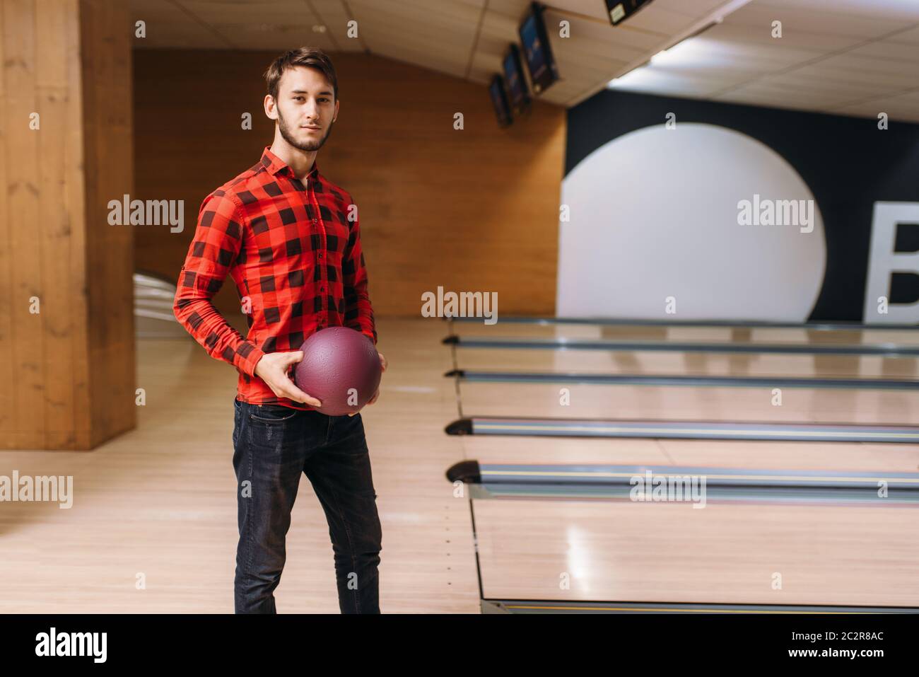 Male bowler standing on lane and holds ball in hands, back view ...