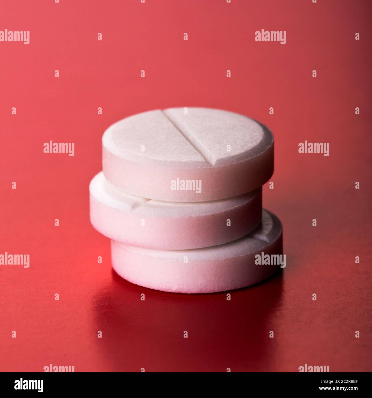Closeup of three white tablets on red Stock Photo - Alamy