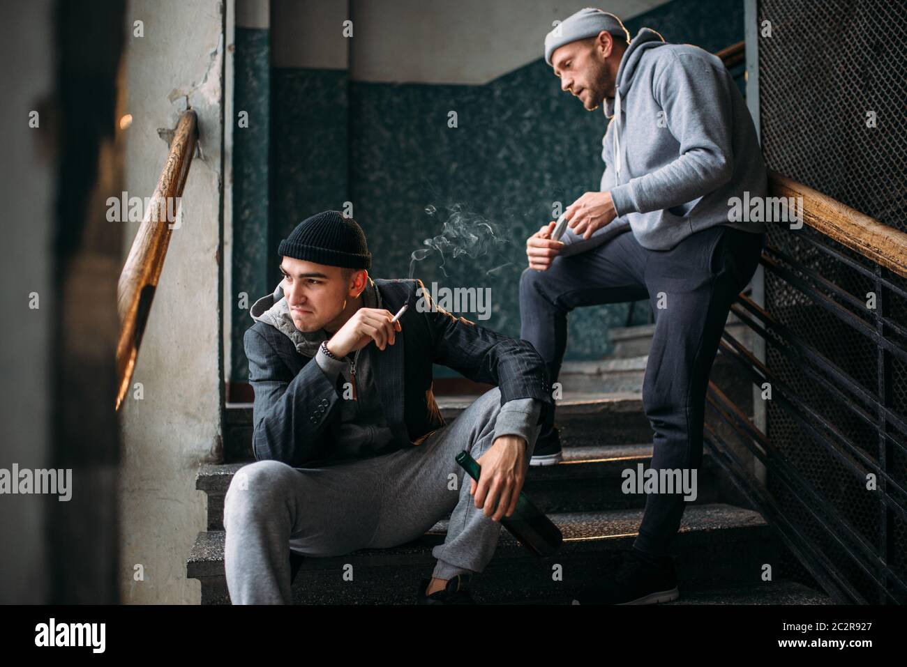 Bad guys waiting for victim on the stairs and smoking. Street robber ...