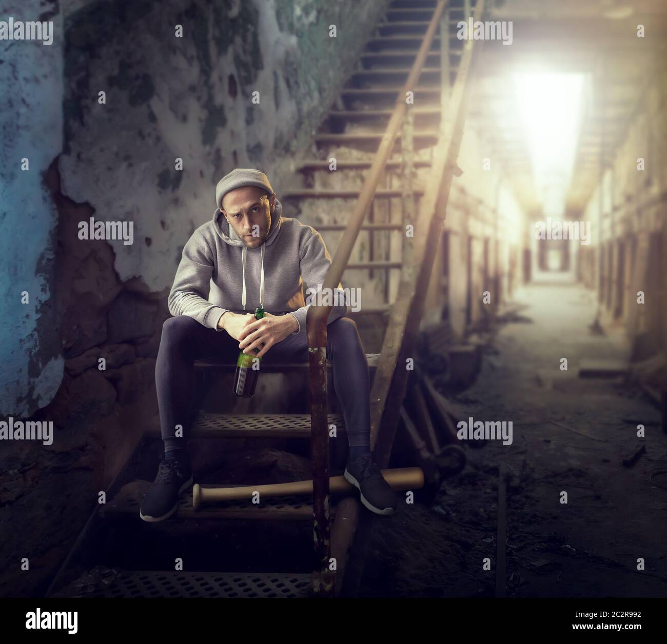 Bad guy with bottle of alcohol sits on stairs. Street robber waiting ...