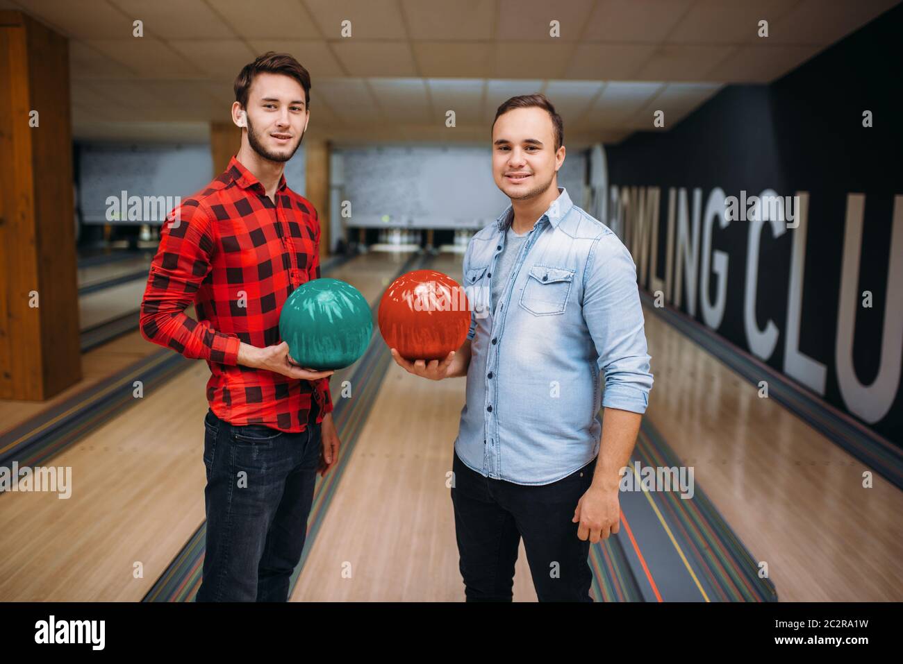 Two male bowlers poses on lane with balls on hands. Bowling alley ...