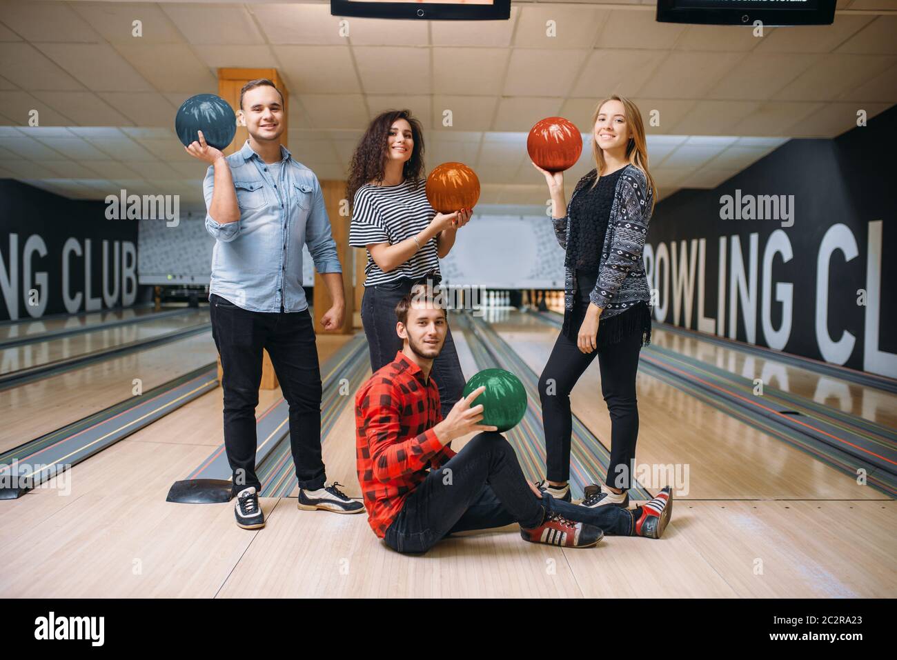 Bowling team poses on lane with balls on hands. Players before ...