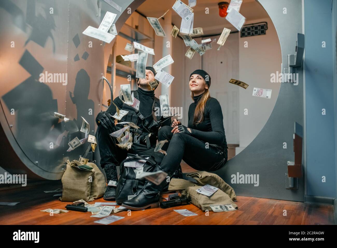 Bank robbery, two happy robbers in black uniform throwing money at the ...