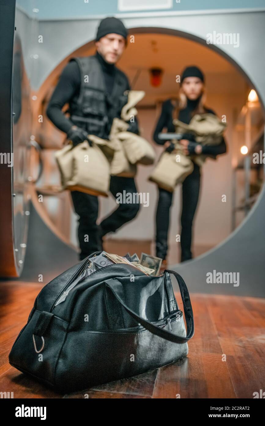 Bank robbery, two robbers in black uniform take out money from vault ...