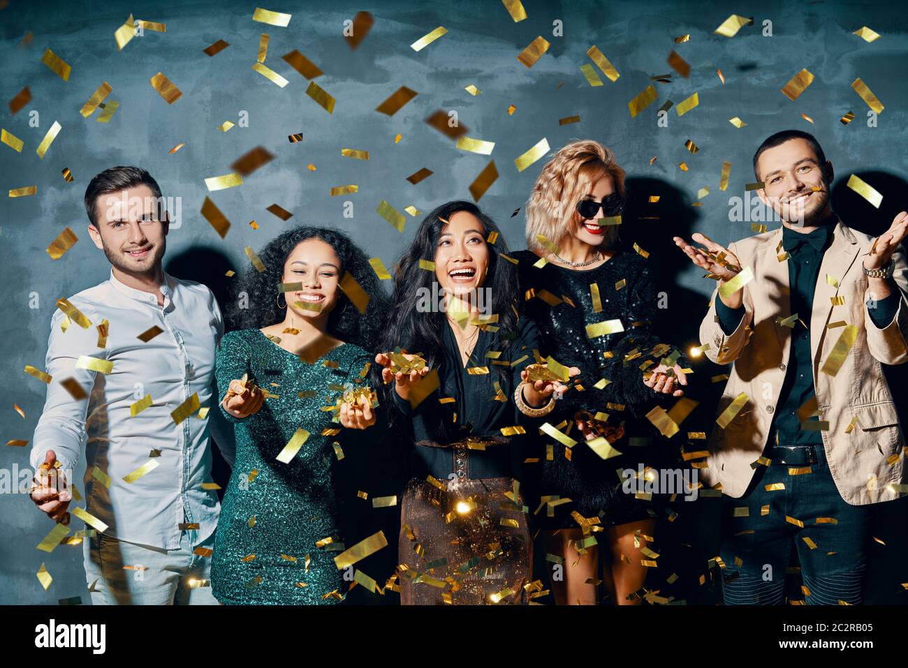 Happy young people dancing and having fun with confetti flying ...