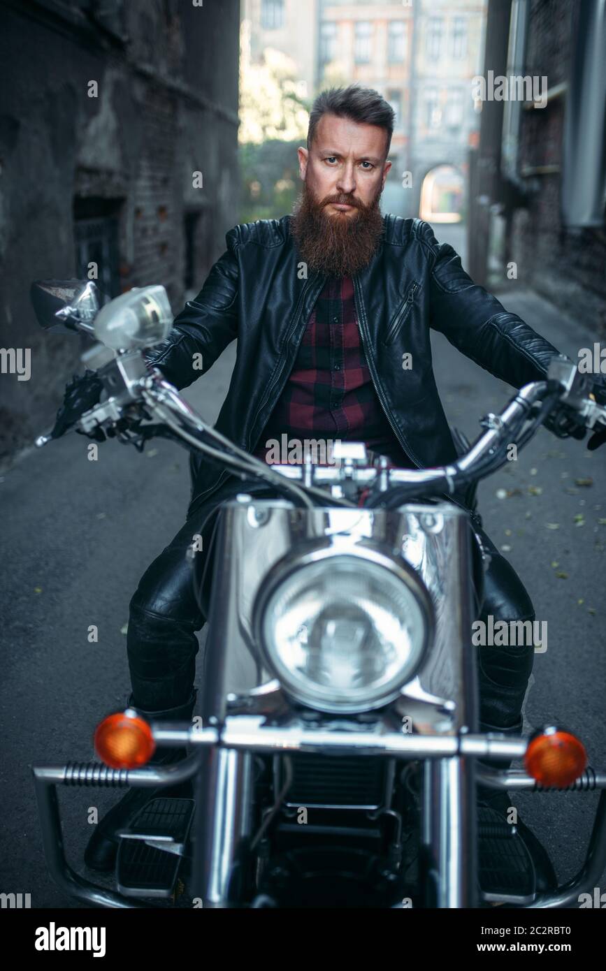 Bearded biker in leather jacket sitting on classical chopper, front ...