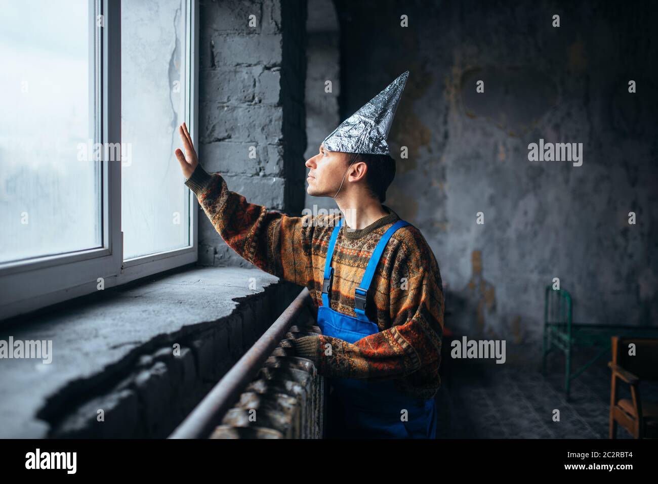 Paranoid man in tinfoil cap looking out the window, mind protection ...