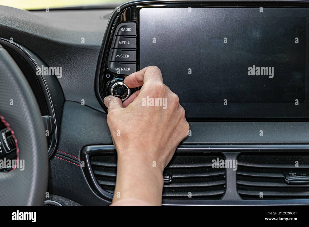 Closeup of woman hand, turning button on car radio for listening to ...