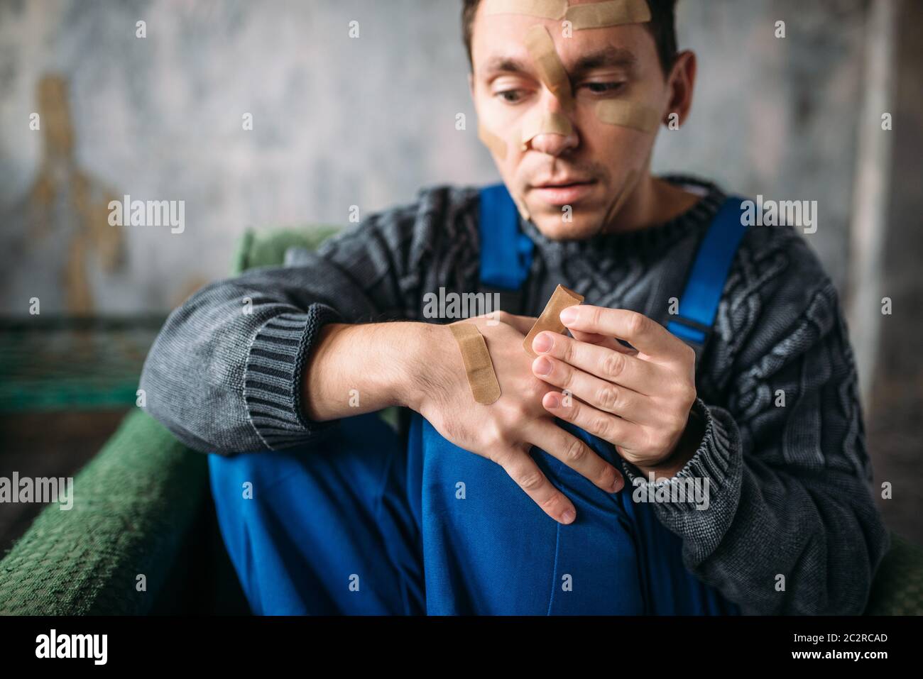 Madman in uniform with plasters on face and hands, psycho patient ...