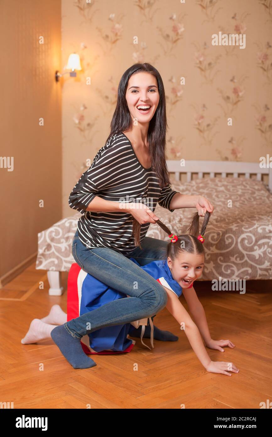 Smiling mother and little girl playing a horse Stock Photo - Alamy