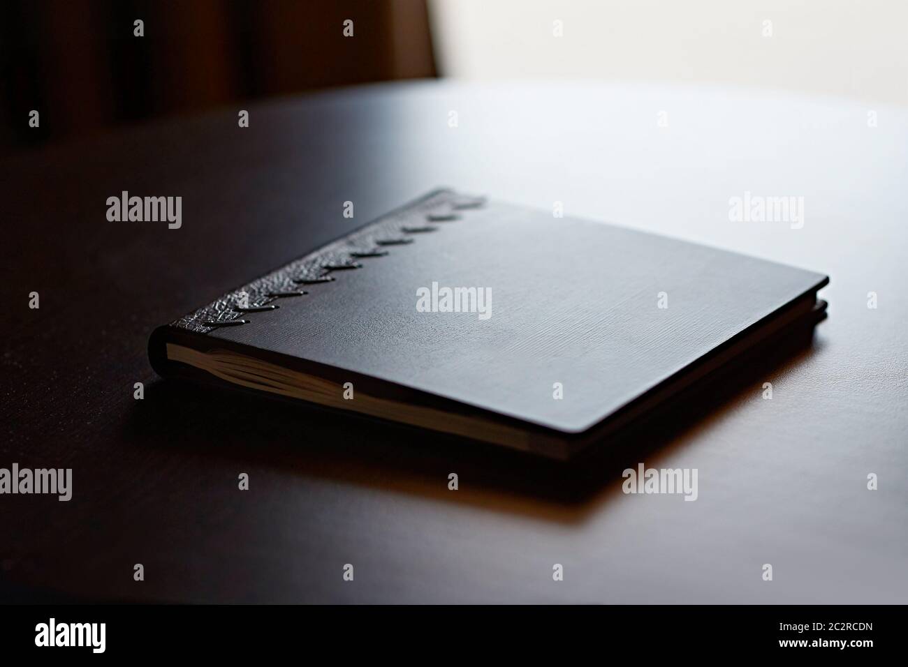 Note book with hard wooden cover on table by the window in natural ...