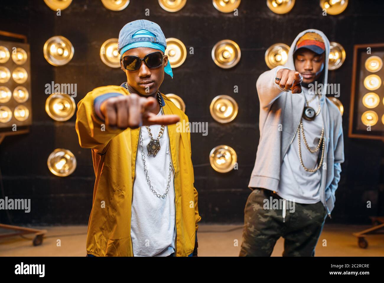 Two black rappers in caps, artists poses on stage with spotlights on ...