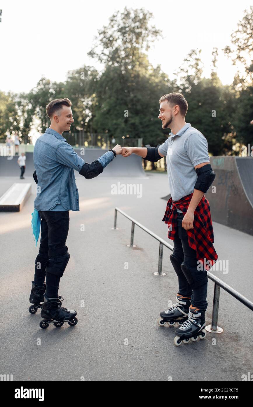 Roller skating, two male skaters rolling in summer park. Urban roller ...