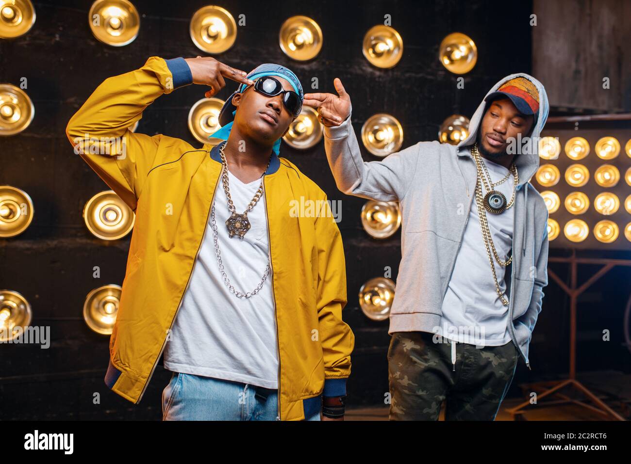 Two Black Rappers In Caps Artists Poses On Stage With Spotlights On