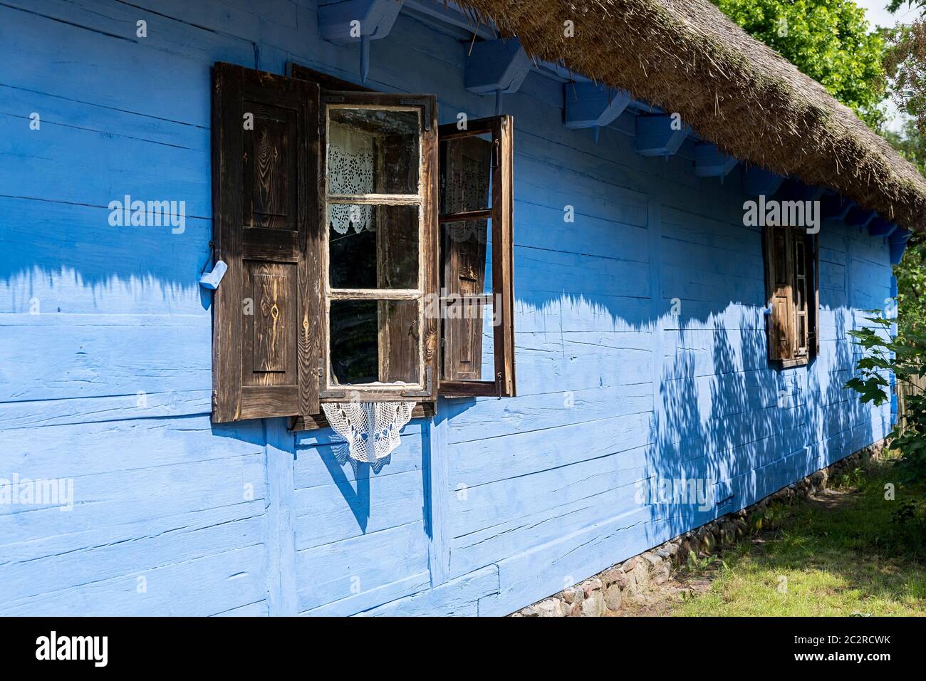 Old rural cottage with wooden windows thatched, painted blue. Open-air ...