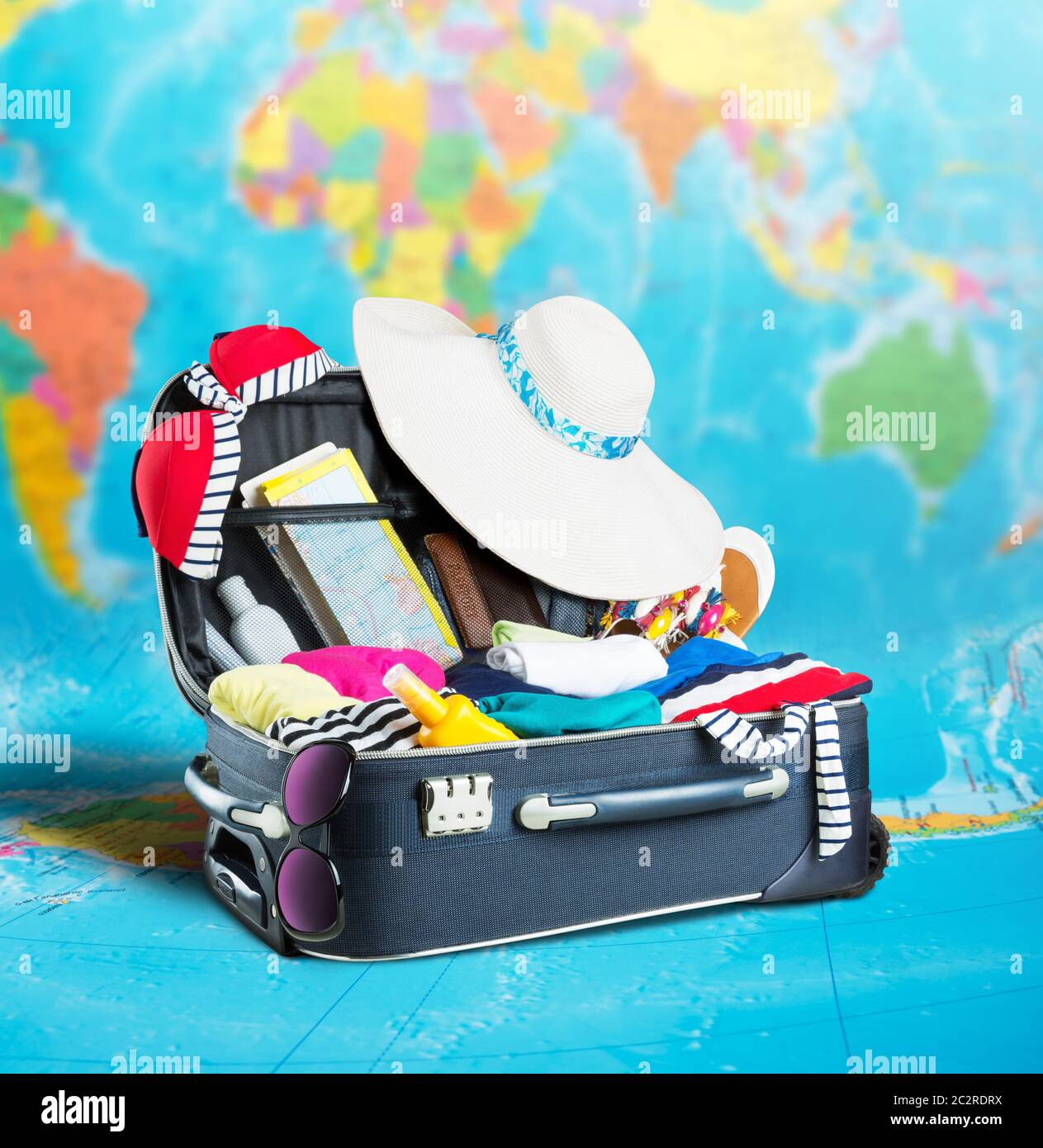 Open suitcase full of clothing on map Stock Photo - Alamy