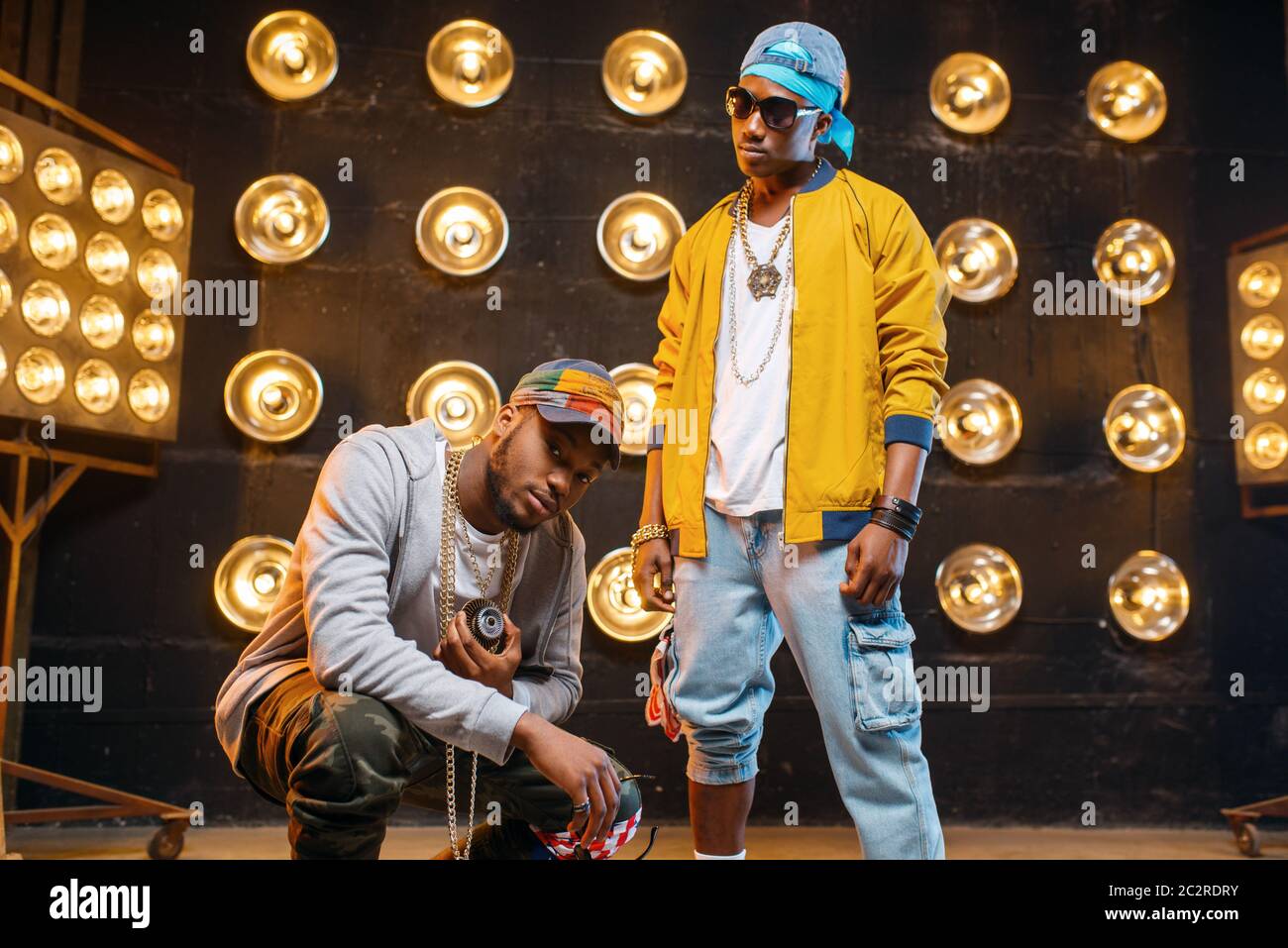 Two black rappers in caps, perfomance in club, stage with spotlights on ...