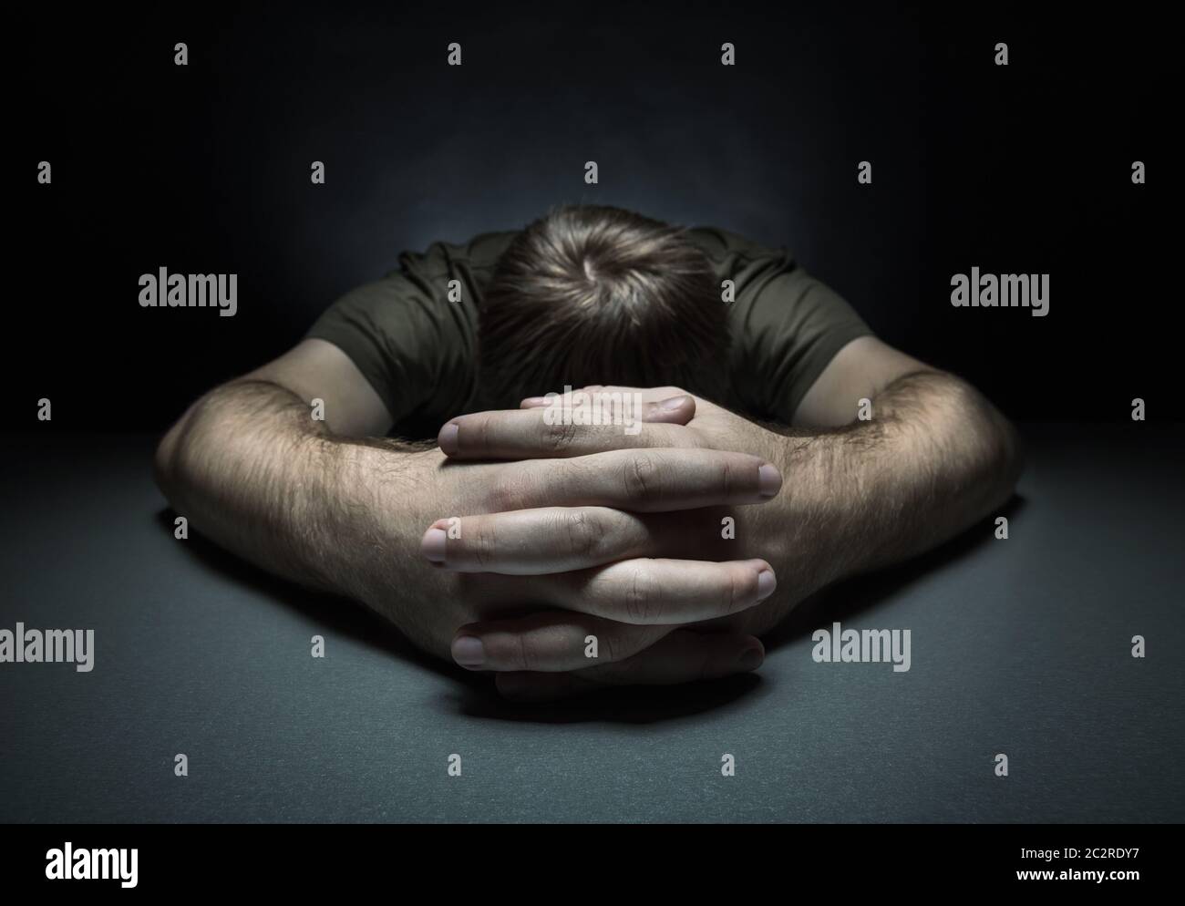 Sad man on the table in dark room Stock Photo - Alamy