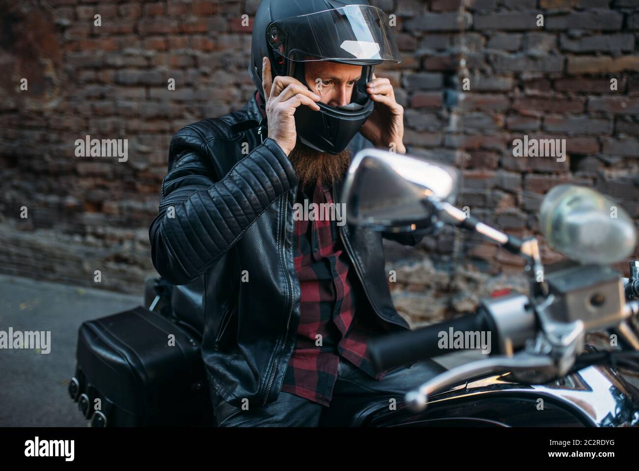Biker puts on helmet before riding on classical chopper. Vintage bike ...